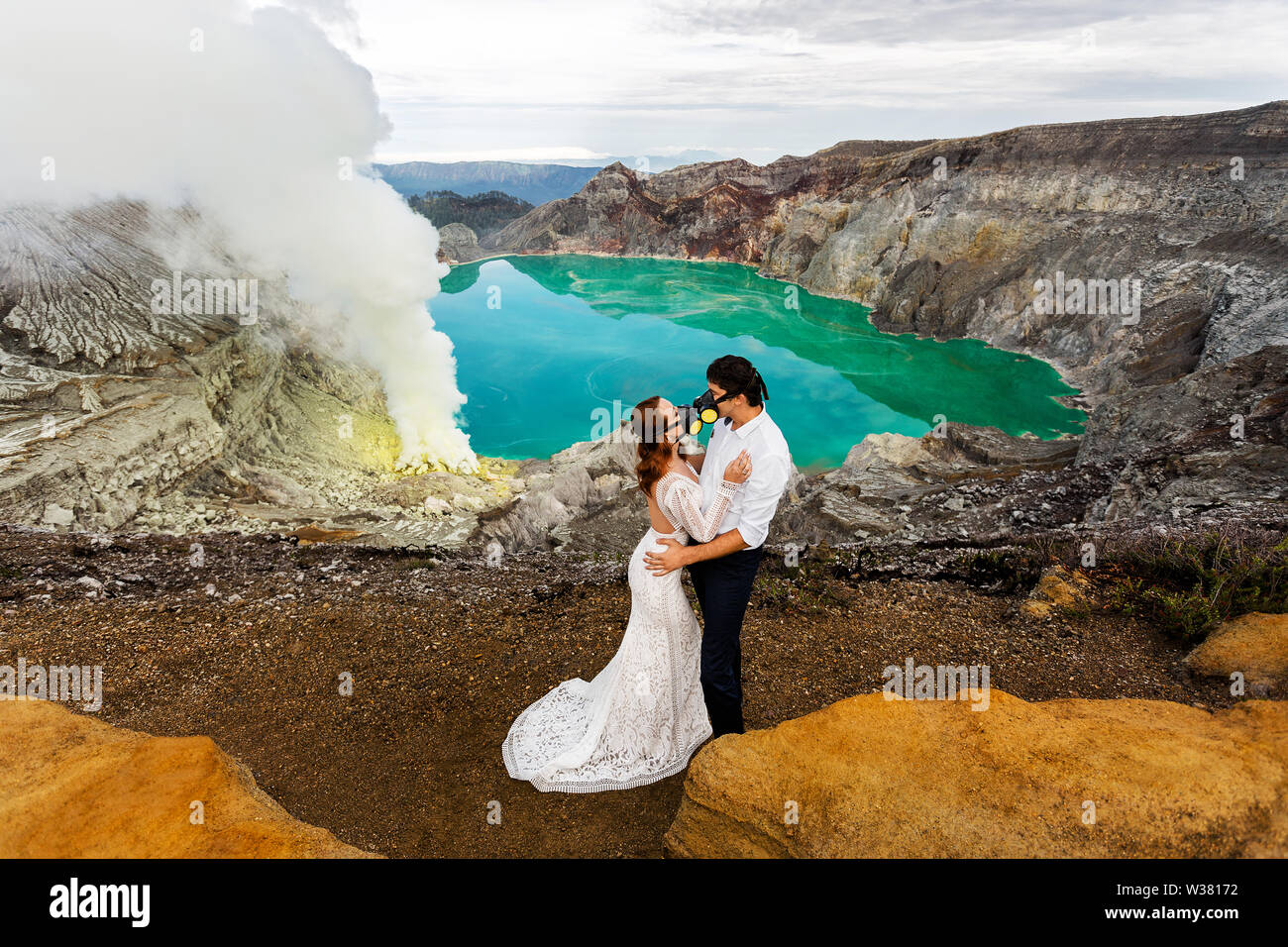 Bride and groom in respirators look at each other in the crater of a ...