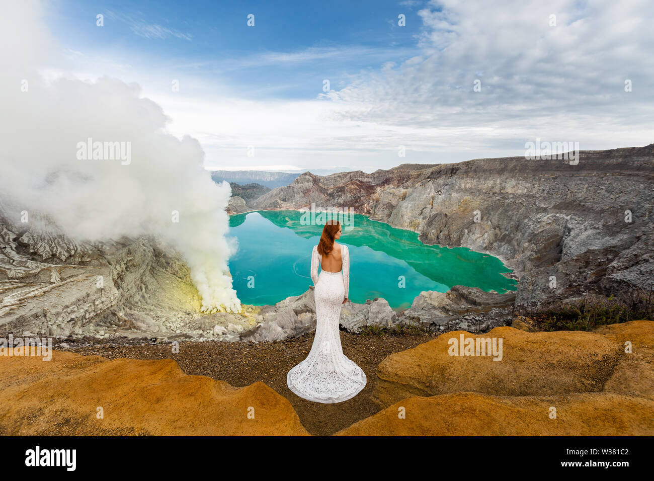 Bride in a white wedding dress on the background of a green volcanic ...