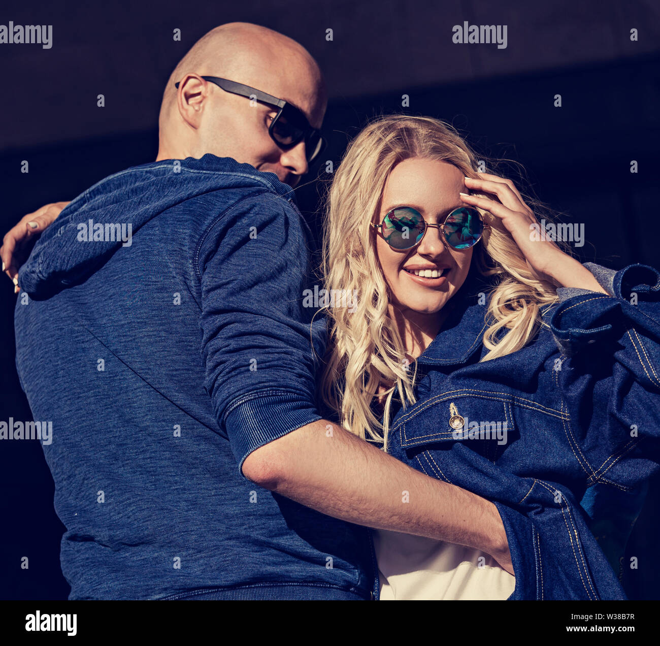 Stilish smiling couple cuddling in modern blue jeans jackets and trendy ...