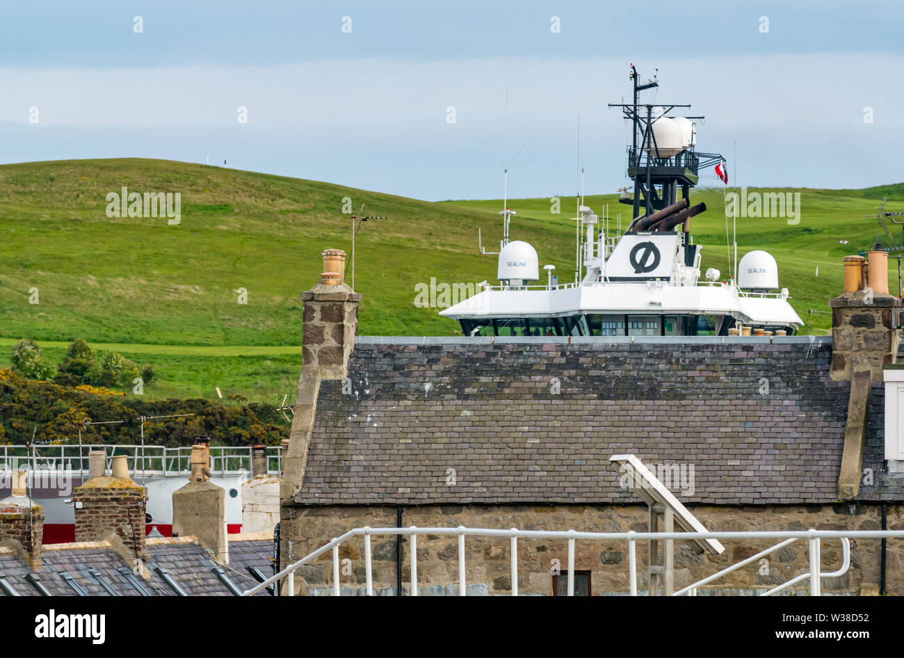 Ship leaving Aberdeen harbour, towering above cottage roofs of Footdee ...
