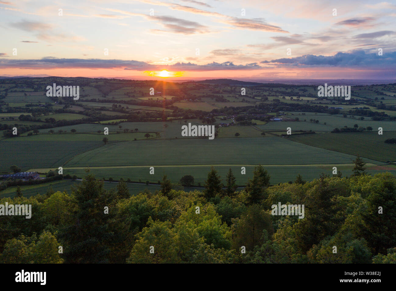 Dramatic sunset over scenic farming fields. Drone shoot over trees in ...