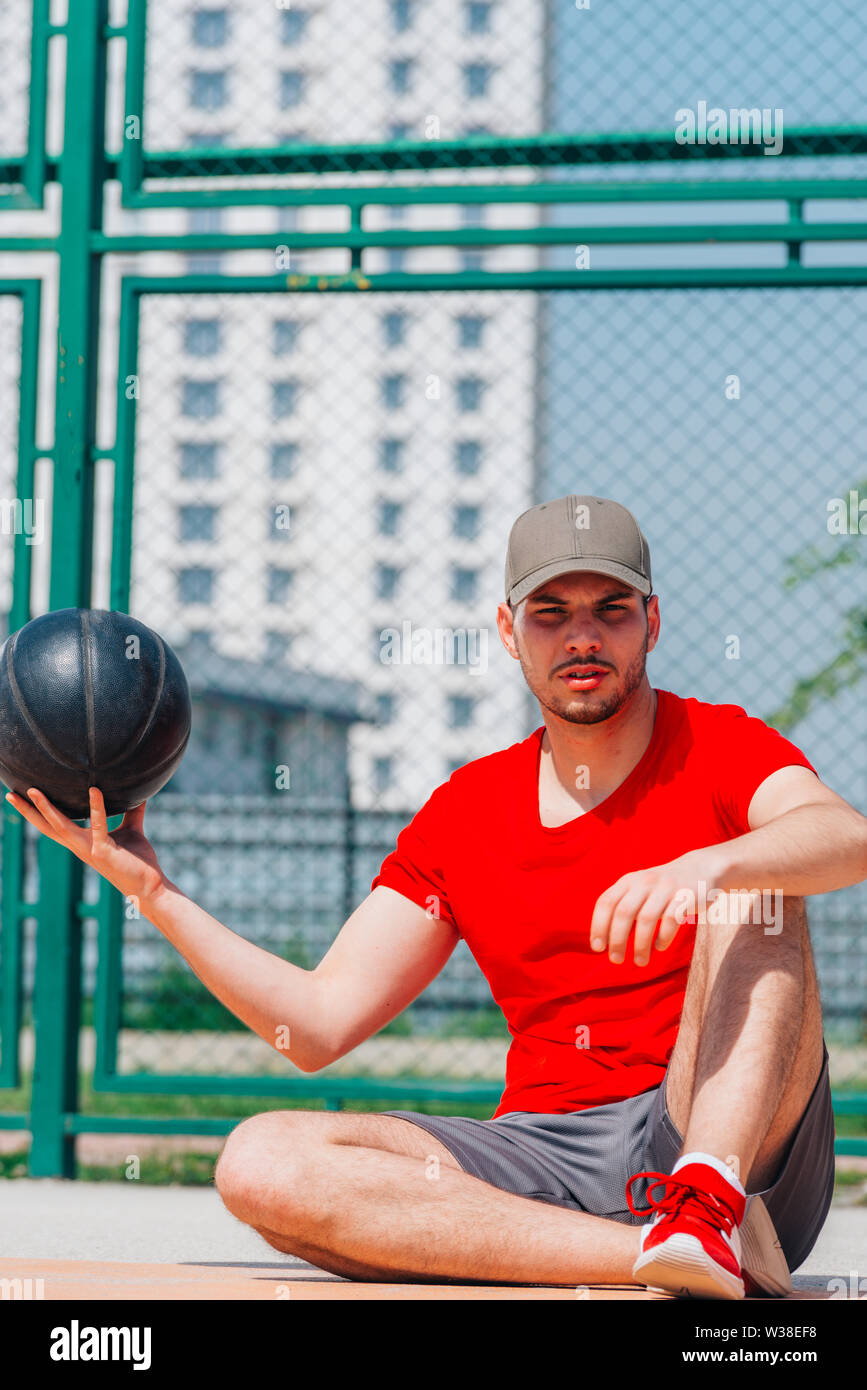 Two basketball players having some rest sitting on the court after an ...