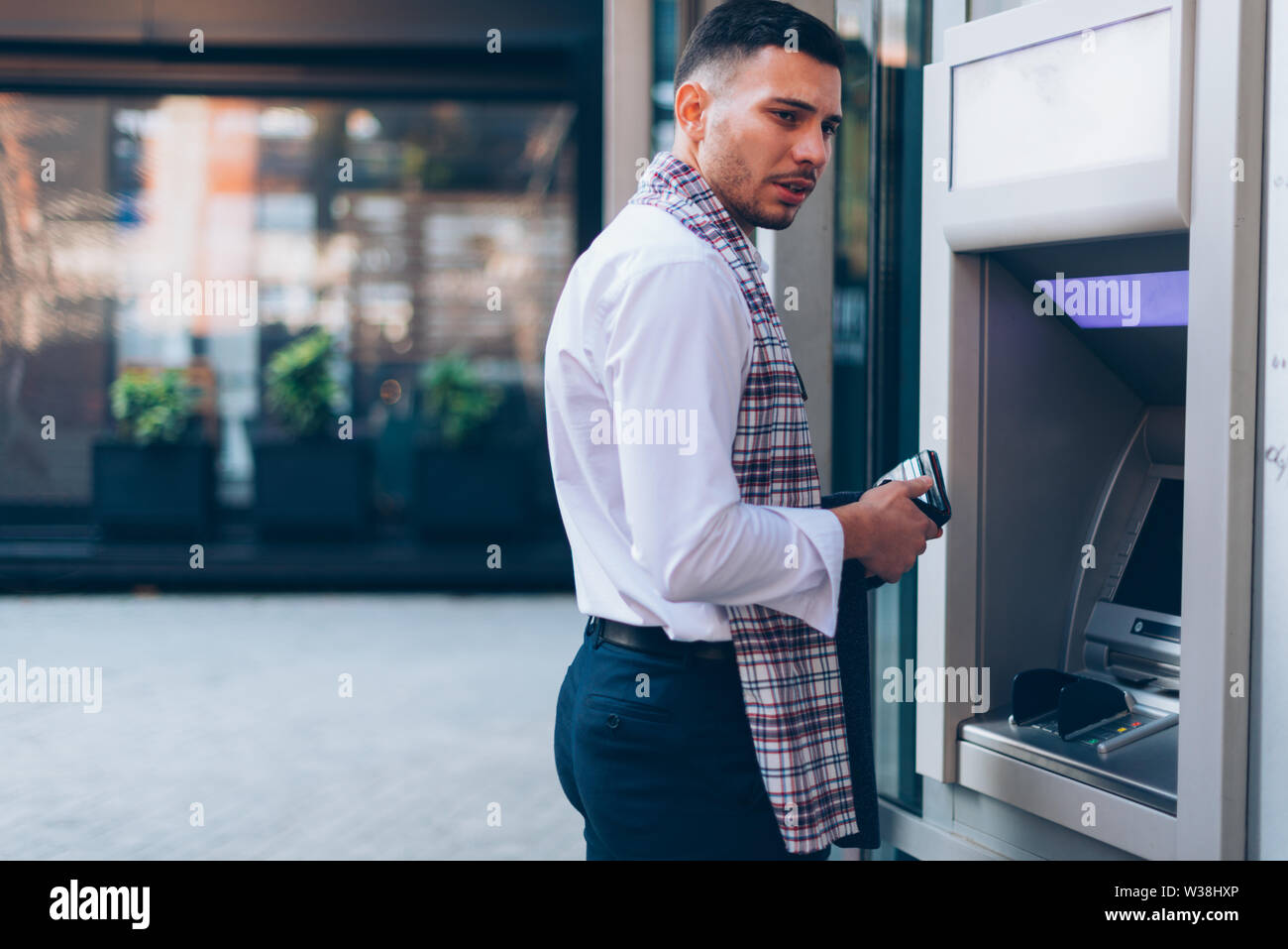 Stylish businessman in white shirt is holding his wallet and standing ...