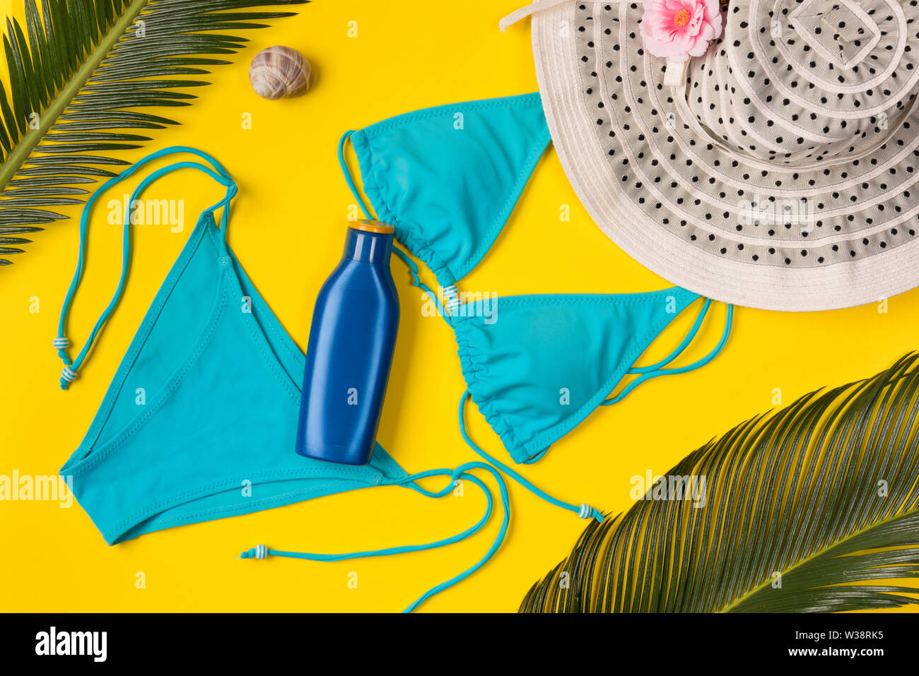 Beach theme on the yellow background. Sunscreen, hat, palm leaves ...