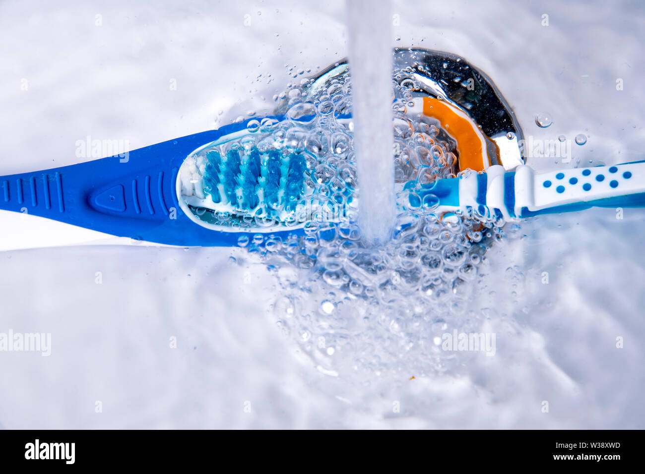 tongue cleaner and toothbrush under running water in the bathroom Stock ...