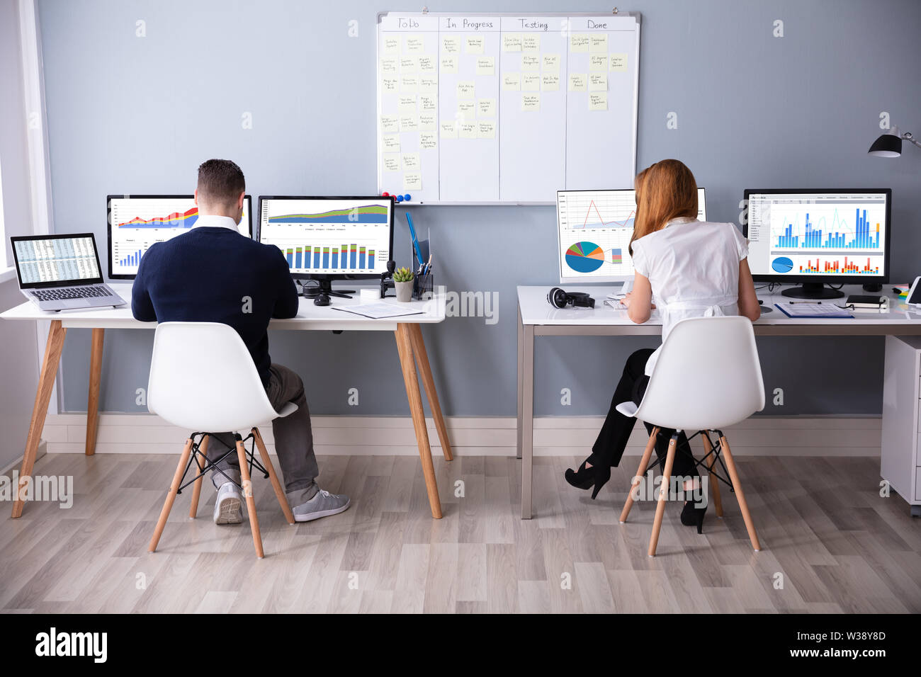 Rear View Of Businessman And Businesswoman Sitting On Chair Using ...