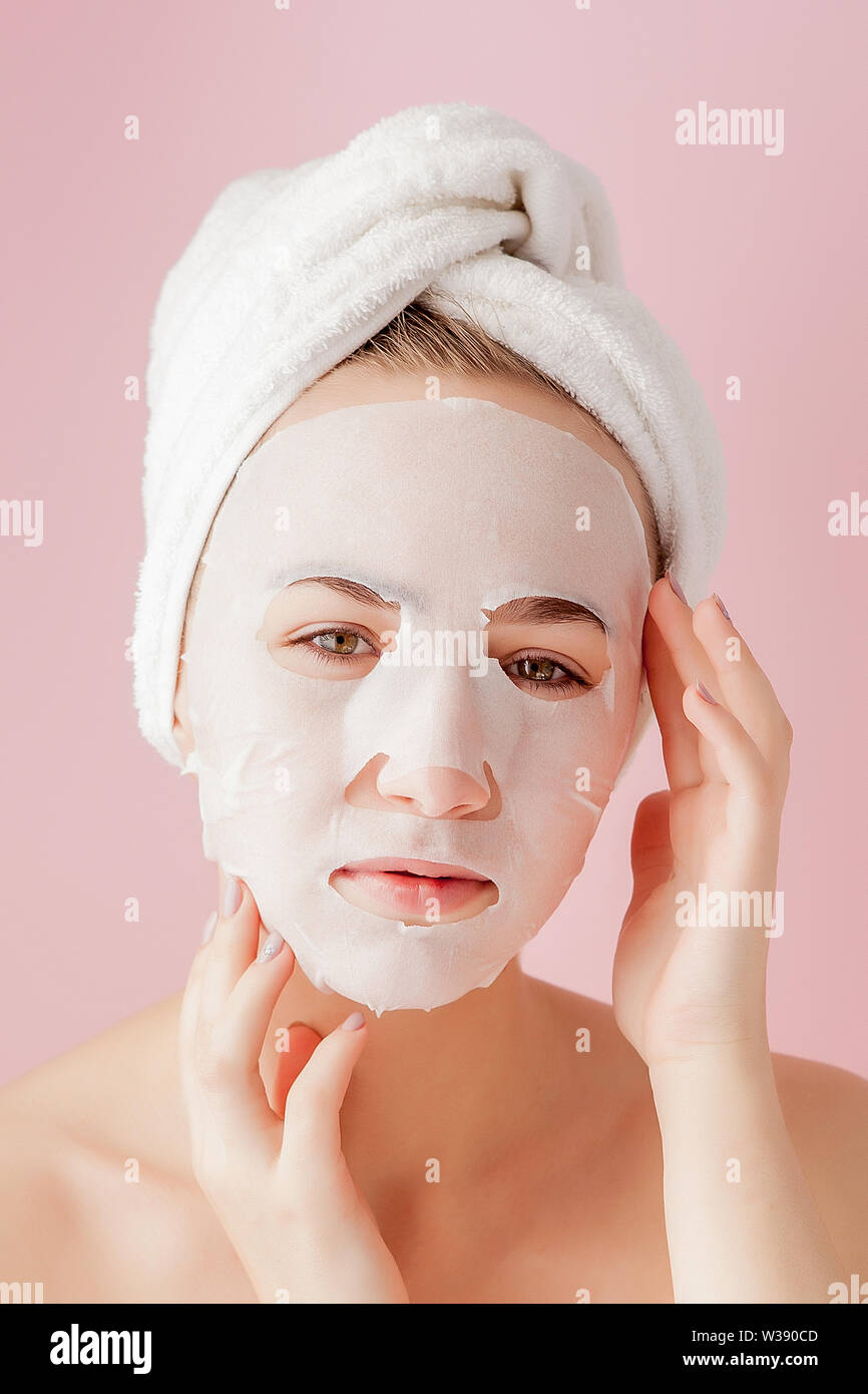 Beautiful young woman is applying a cosmetic tissue mask on a face on a ...