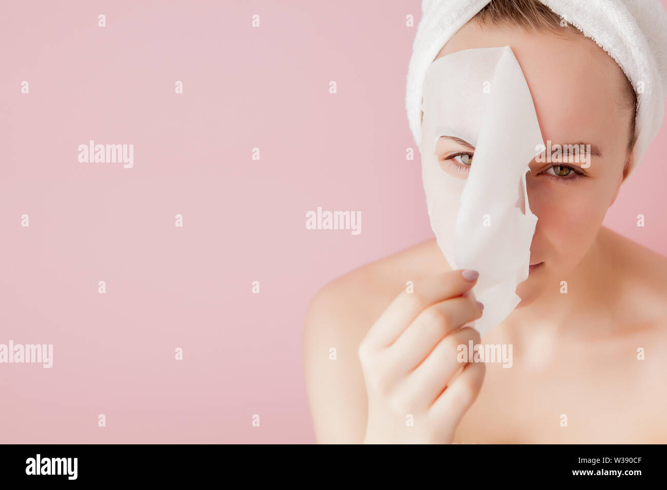 Beautiful young woman is applying a cosmetic tissue mask on a face on a ...
