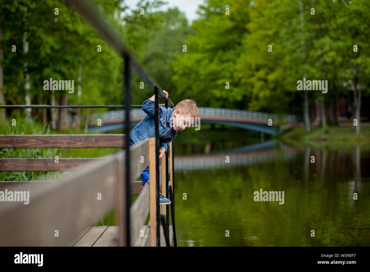 A little boy climbs a bridge railing in the park. The threat of ...