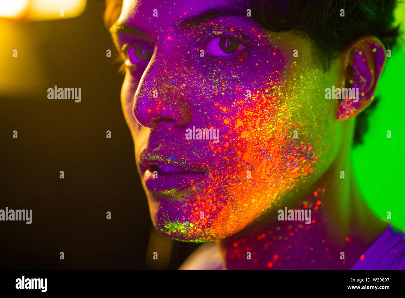 Portrait of fashionable man with colored fluo painting on the face ...
