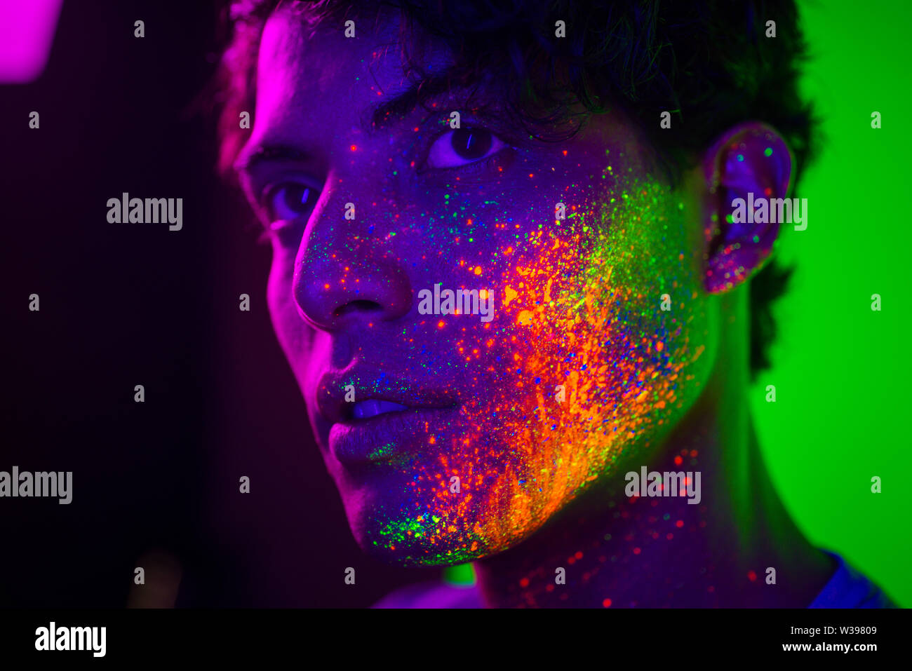 Portrait of fashionable man with colored fluo painting on the face ...