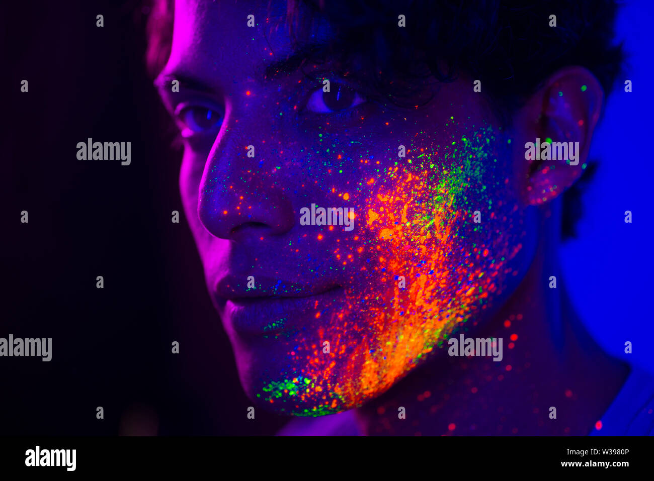 Portrait of fashionable man with colored fluo painting on the face ...