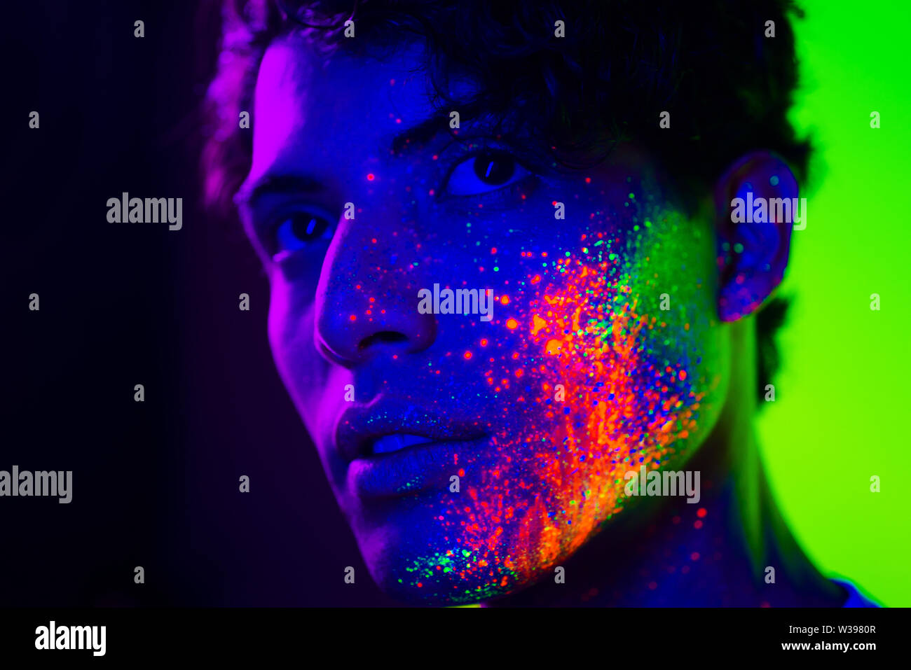 Portrait of fashionable man with colored fluo painting on the face ...