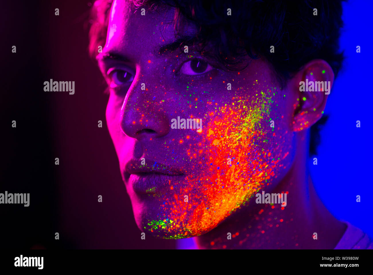 Portrait of fashionable man with colored fluo painting on the face ...