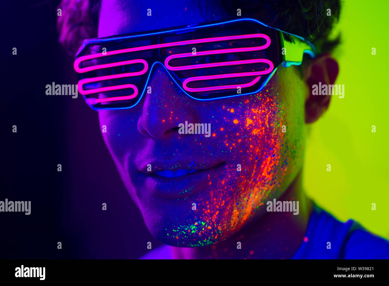 Portrait of fashionable man with colored fluo painting on the face ...