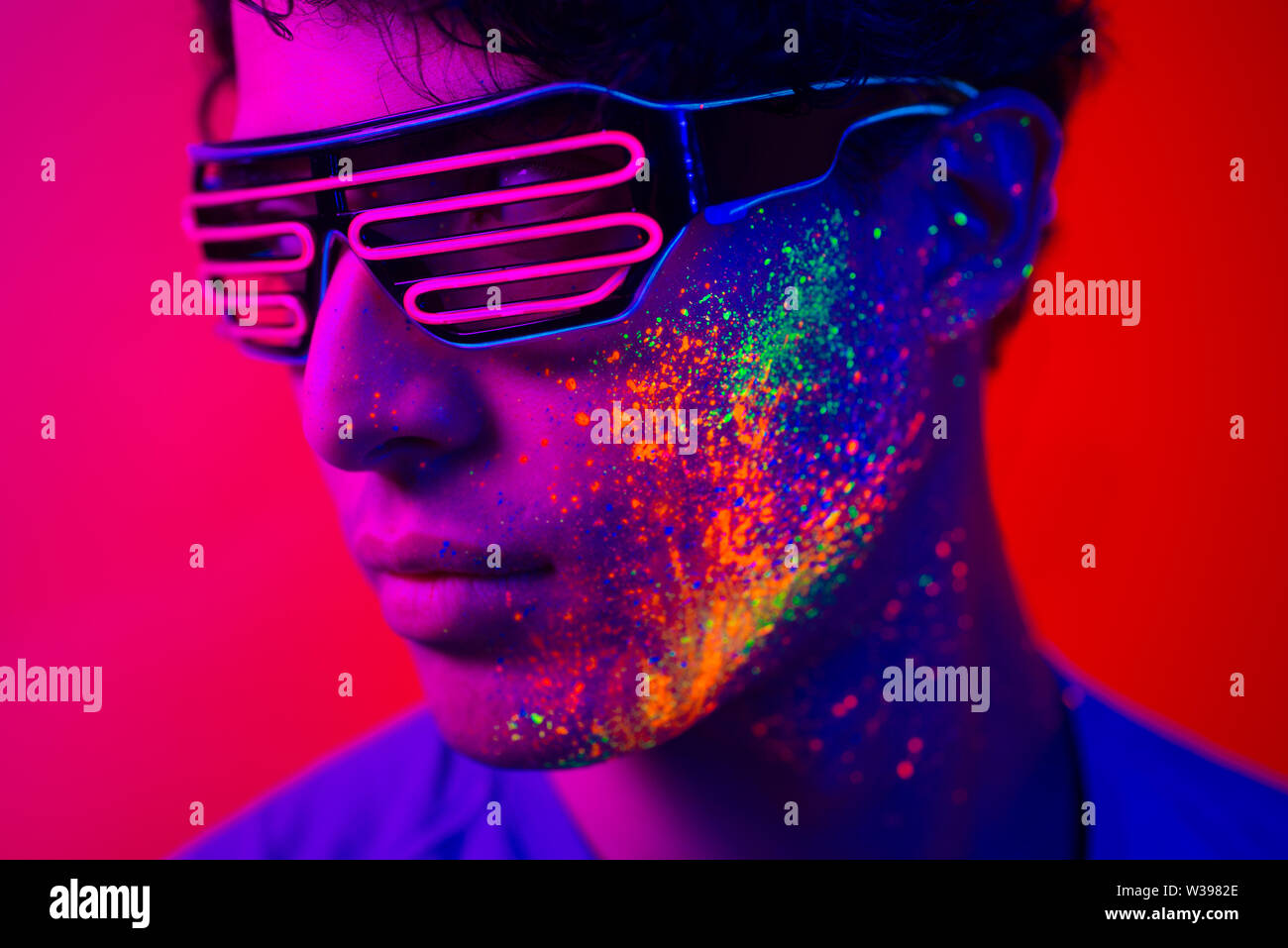 Portrait of fashionable man with colored fluo painting on the face ...