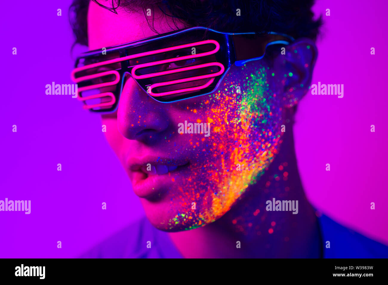 Portrait of fashionable man with colored fluo painting on the face ...