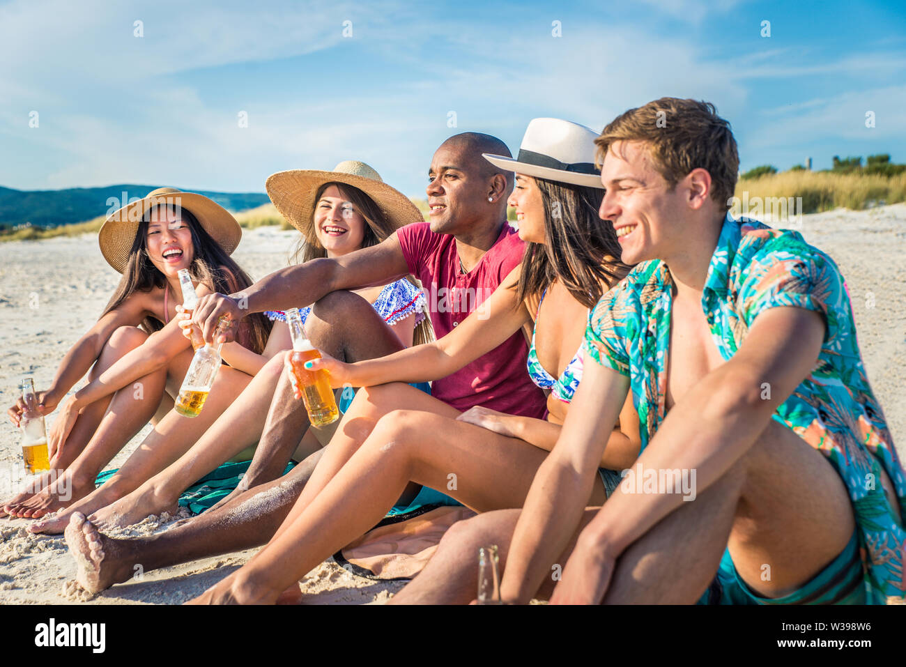 Group of friends having fun on the beach - Young and happy tourists bonding outdoors, enjoying ...