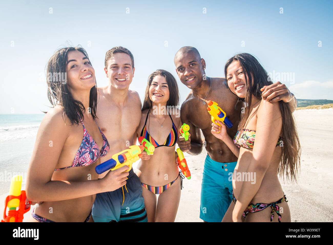 Group of friends having fun on the beach - Young and happy tourists bonding outdoors, enjoying ...