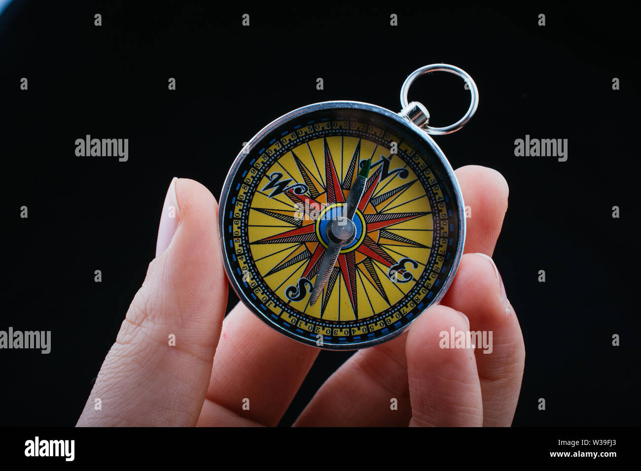 Hand is holding a magnetic compass on black background Stock Photo - Alamy
