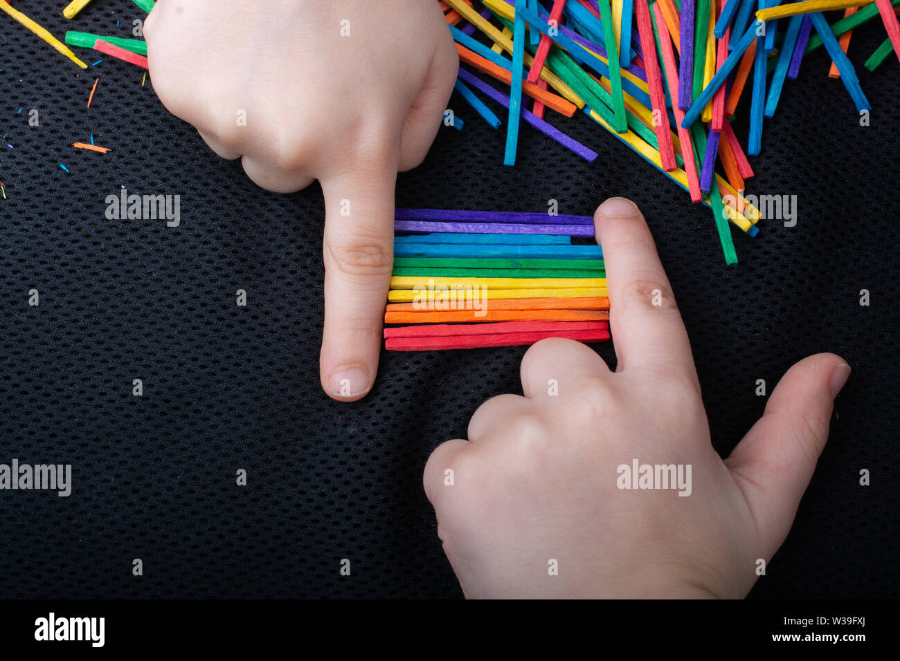 Kid playing with coloured wooden sticks for creativity on white ...