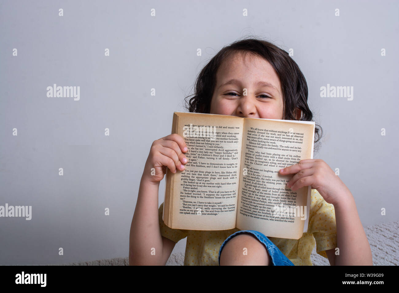 Boy covering face with book as education studying concept Stock Photo ...