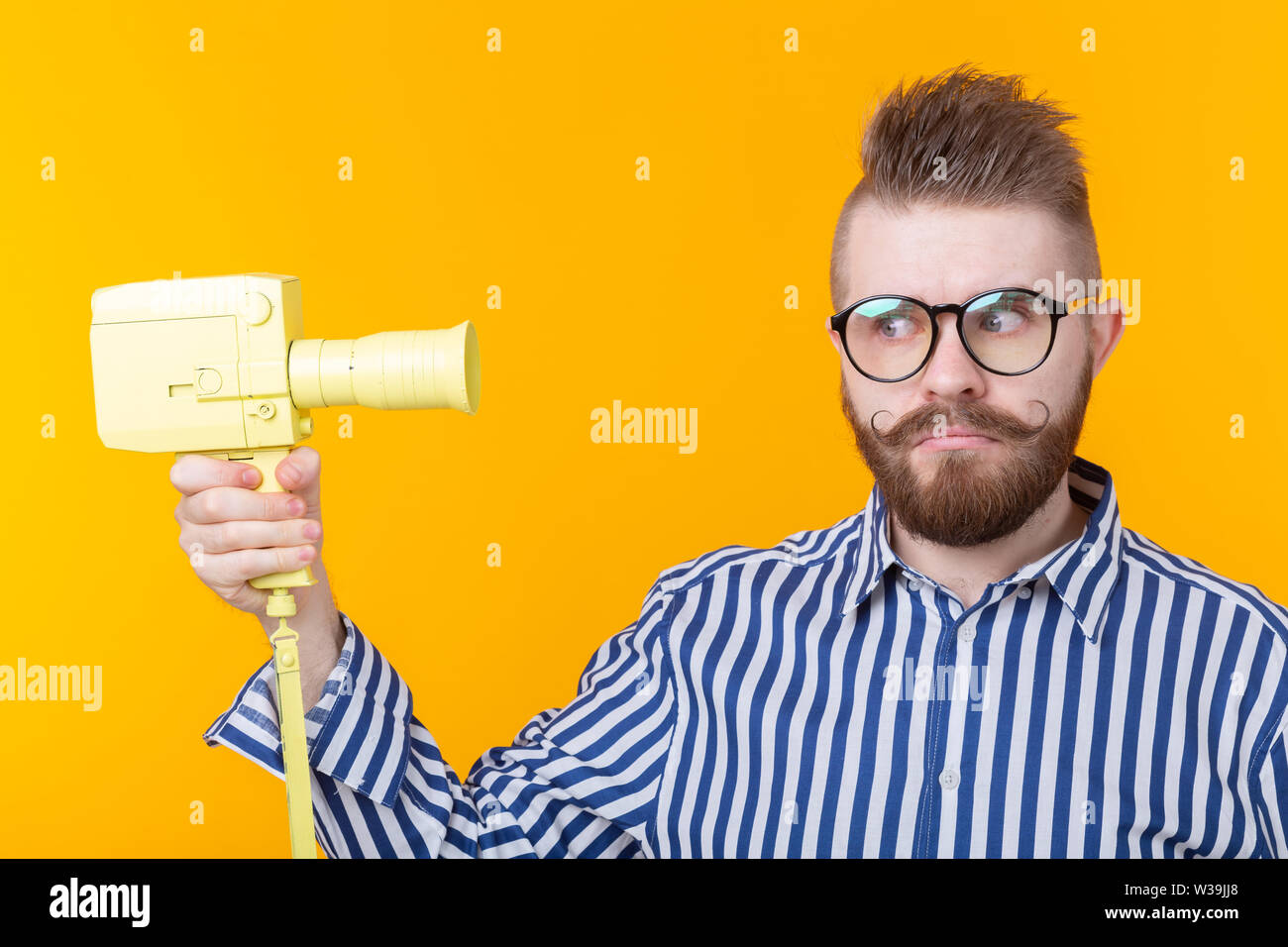 Young tired male videographer is showing a pistol from his yellow ...