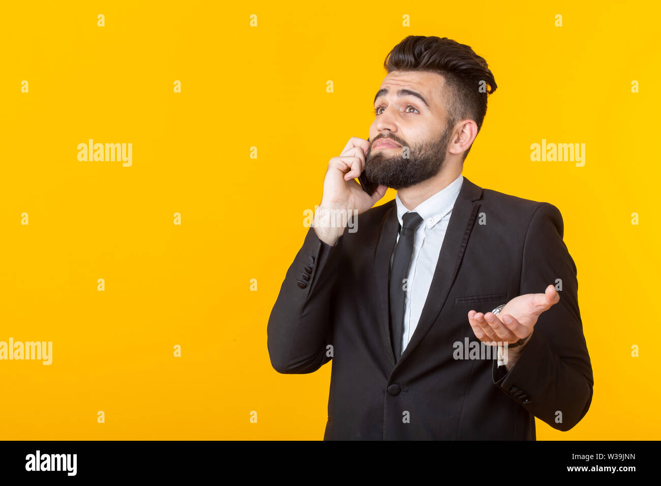 Cute young man with a beard in formal clothes talking on the phone ...