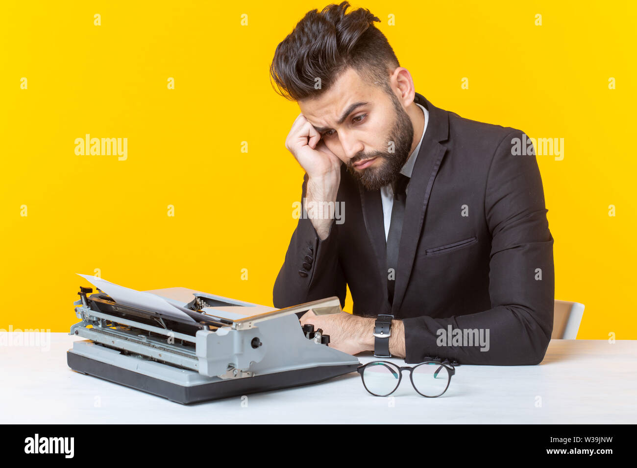 Young pensive tired business man or manager types a document on a ...
