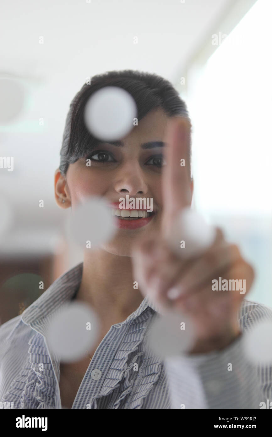 Indian businesswoman touching glass window and smiling Stock Photo - Alamy
