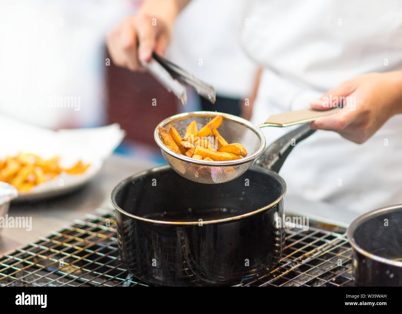 Chef is cooking french fries in the kitchen, Chef cooking fried potato ...