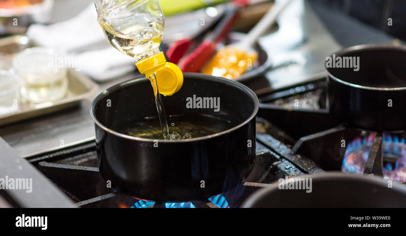 Chef pouring oil in frying pan, Chef cooking food in the kitchen Stock ...