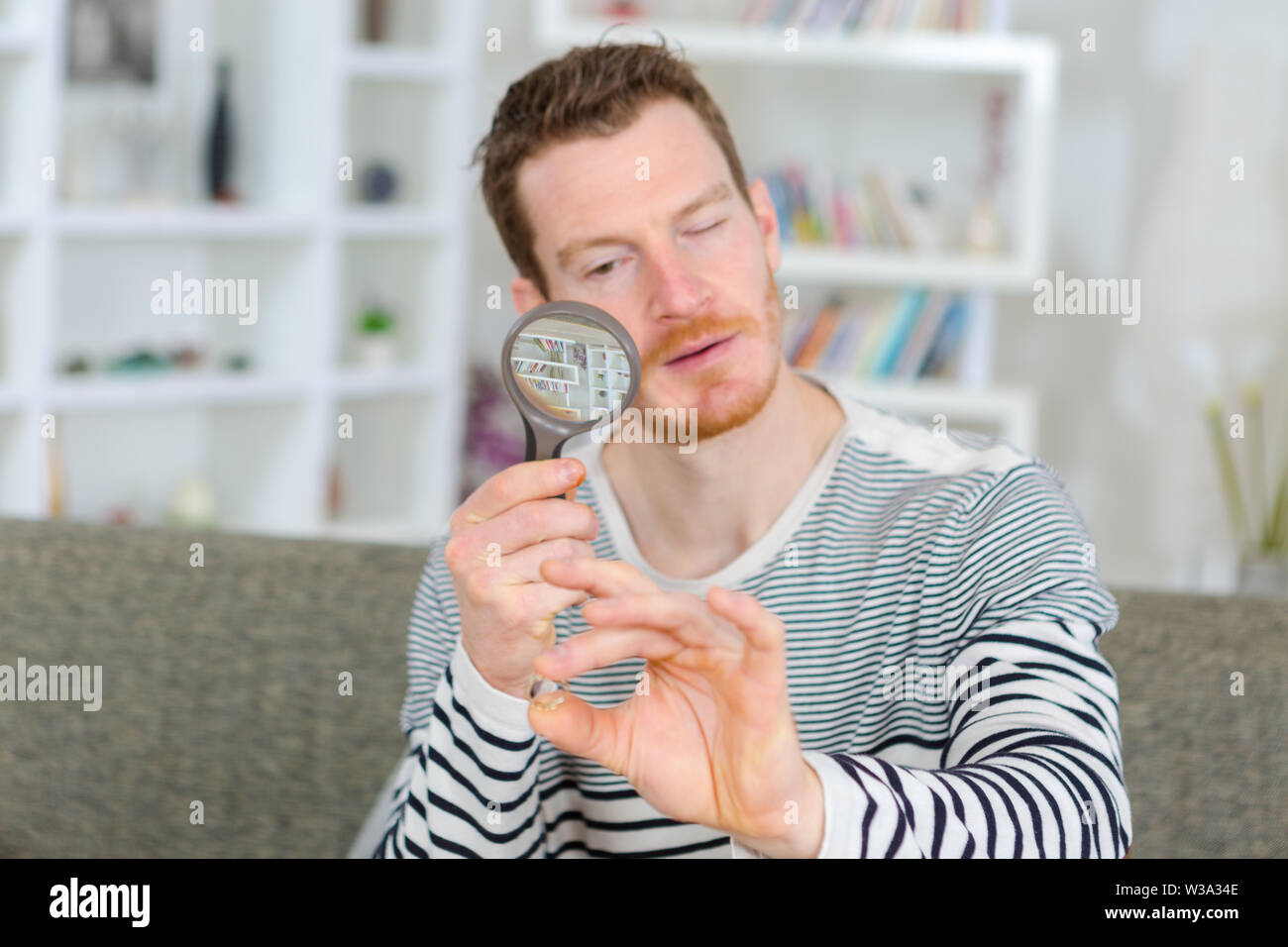man looking at ring through magnifying glass Stock Photo - Alamy