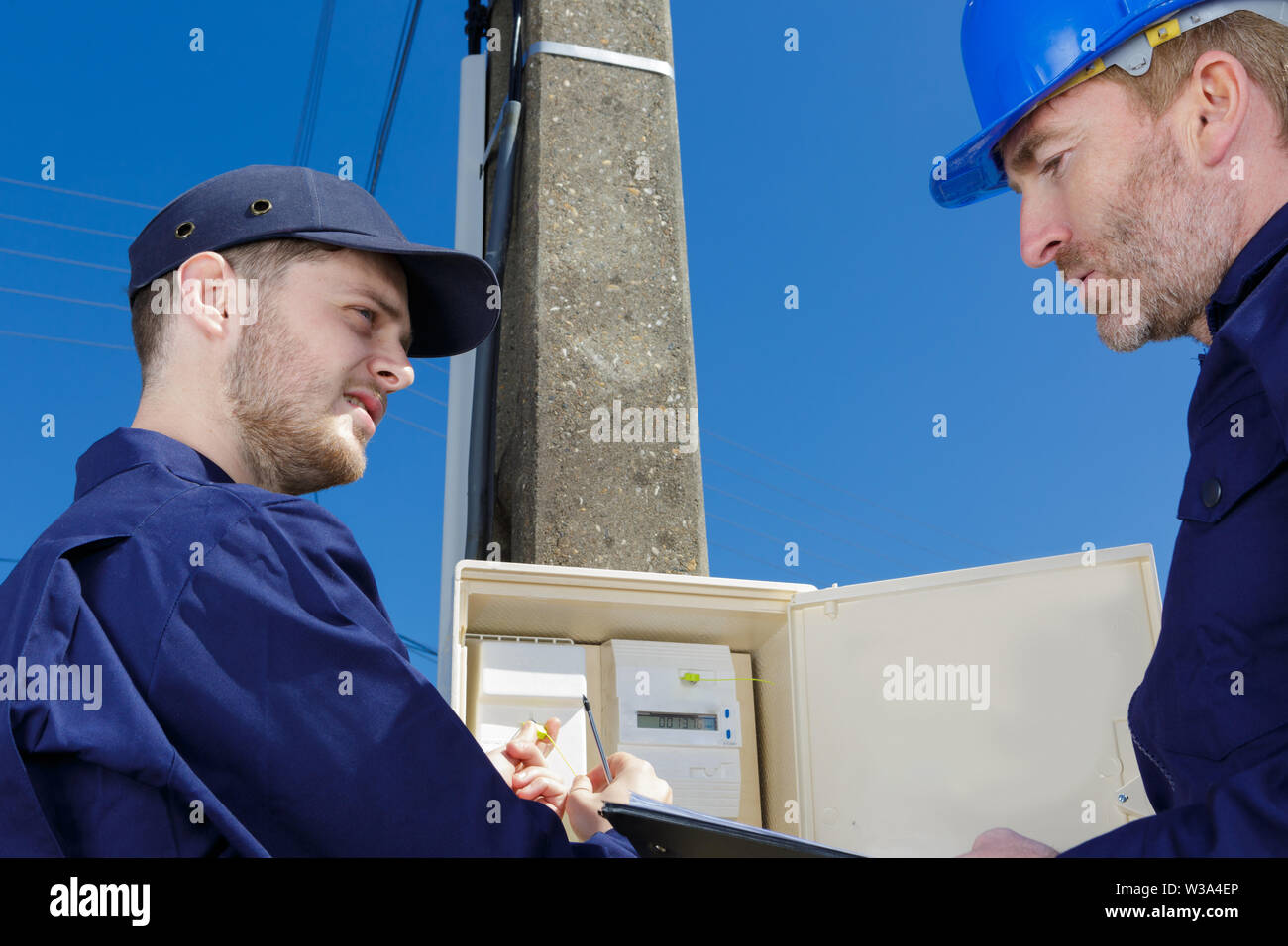 two male technicians looking at outdoor electric meter Stock Photo - Alamy