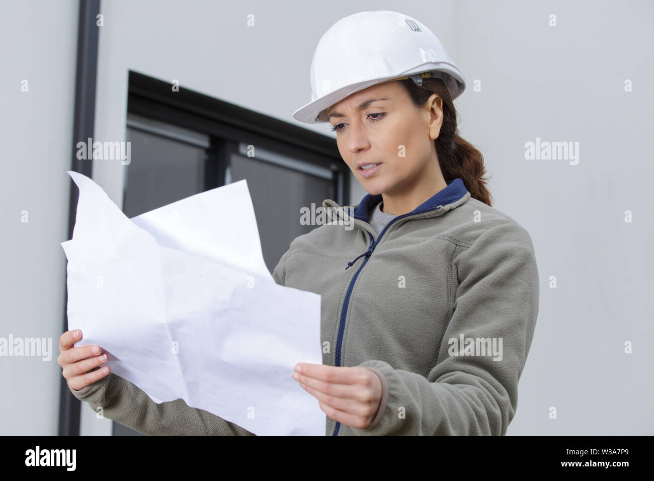 joyful energetic female worker looking at plans Stock Photo - Alamy