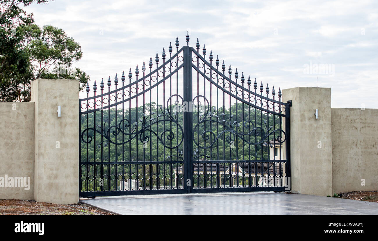 Black metal wrought iron driveway property entrance gates set in ...