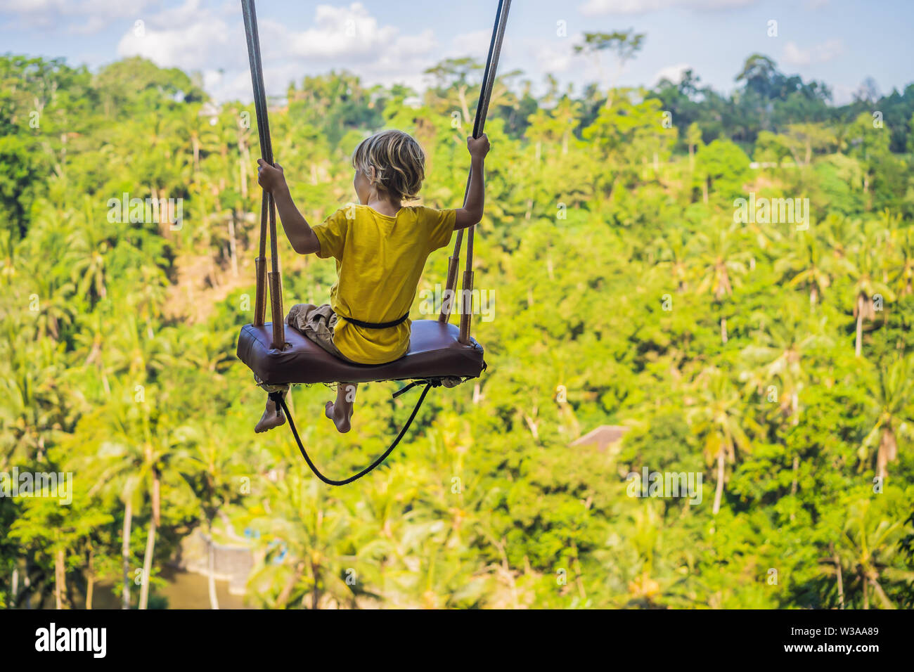 Young boy swinging in the jungle rainforest of Bali island, Indonesia ...