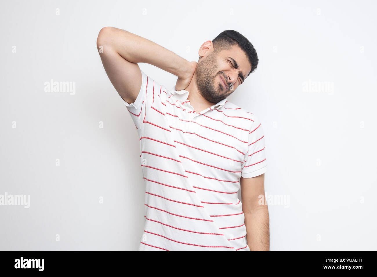 Neck ache or pain. Portrait of handsome bearded young man in striped t ...