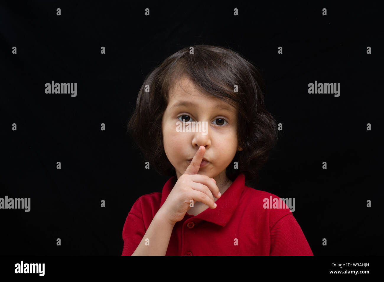 Cute kid put index finger over lips for quiet gesture Stock Photo - Alamy