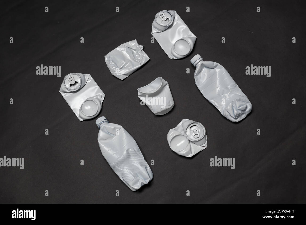 Crumpled plastic and metal cans lie on a black background. Concept of ...