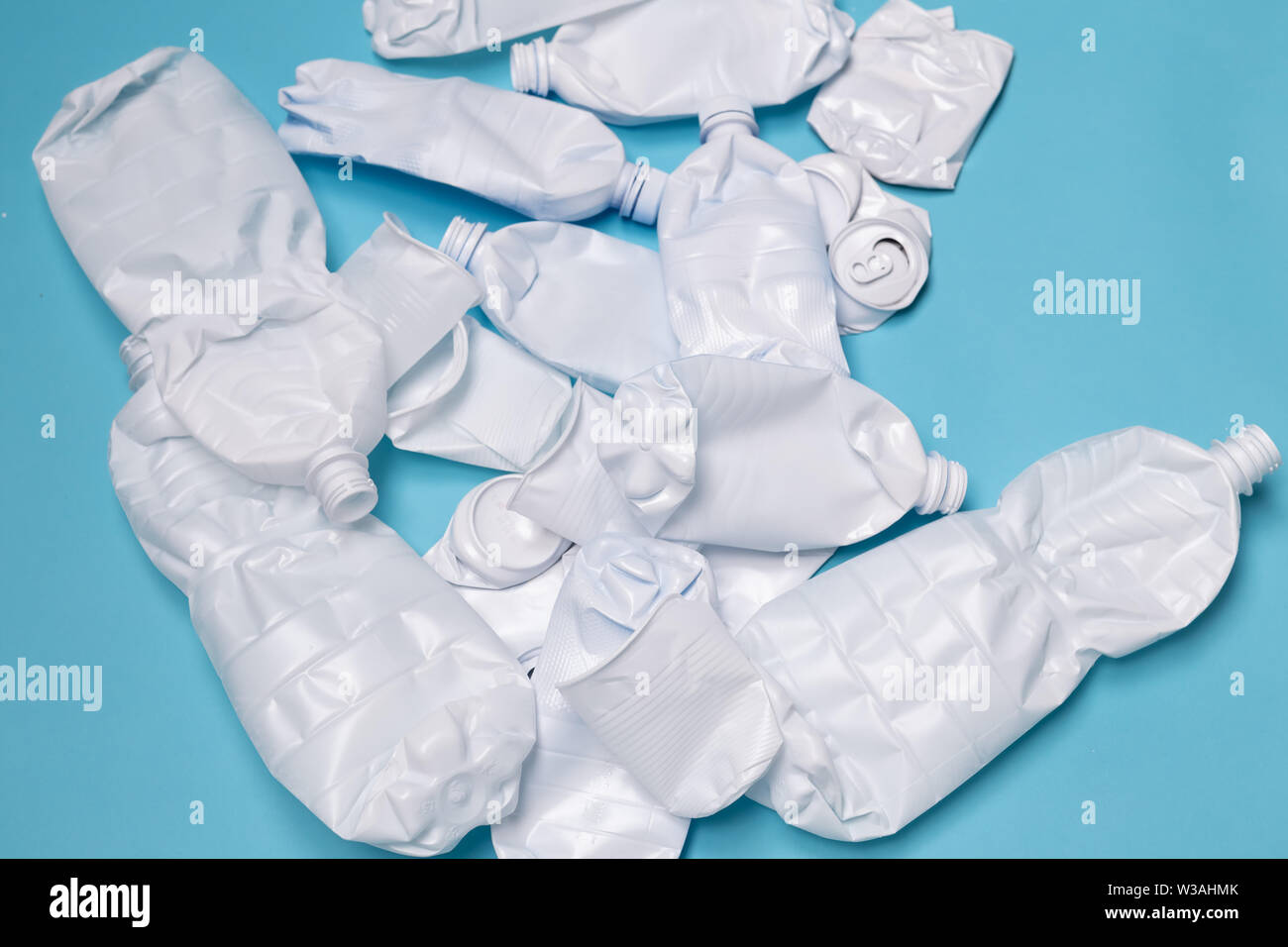 Crumpled plastic and metal cans lie on a blue background. Concept of ...