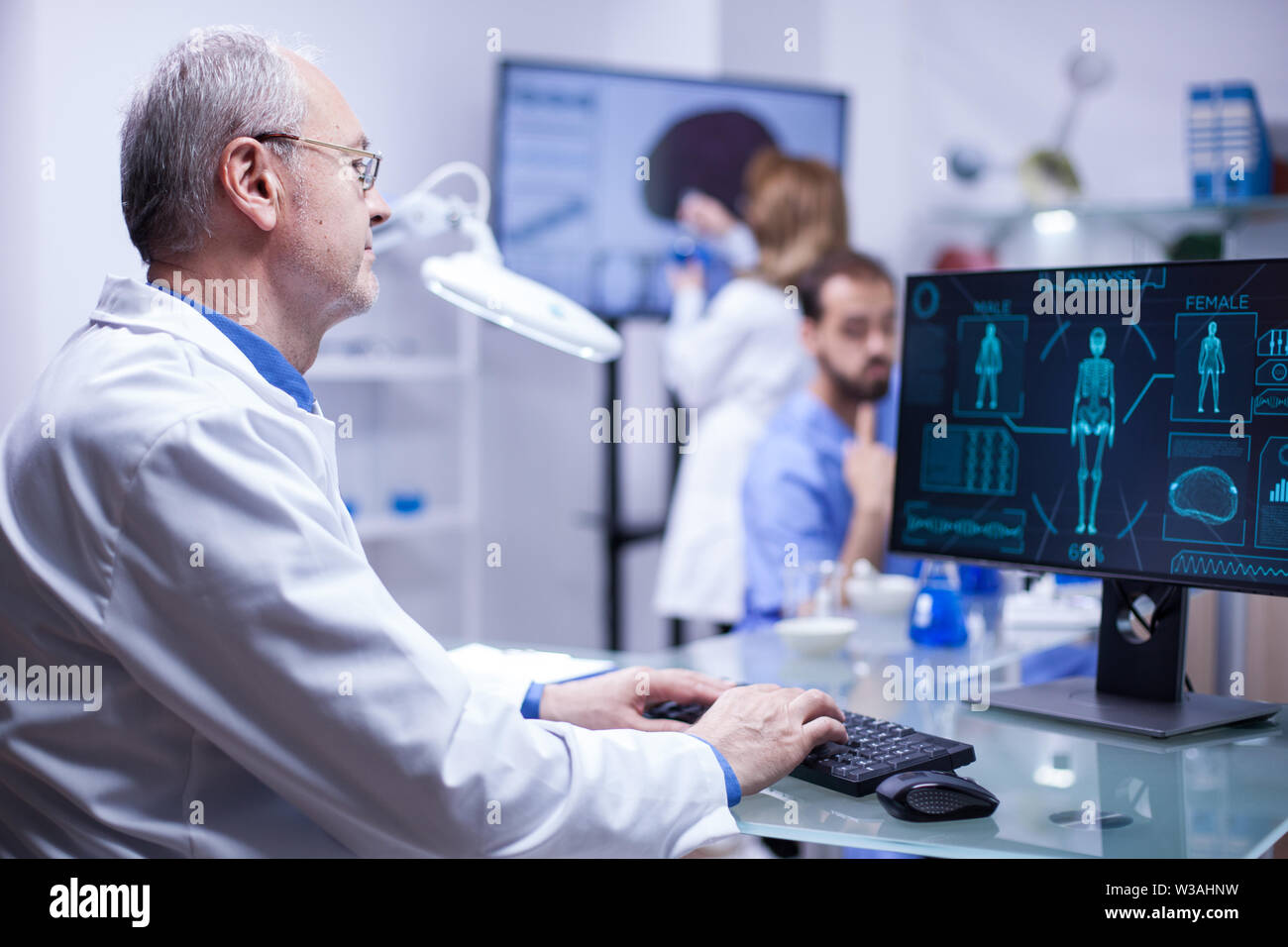 Experienced senior scientist typing the data in computer from last ...