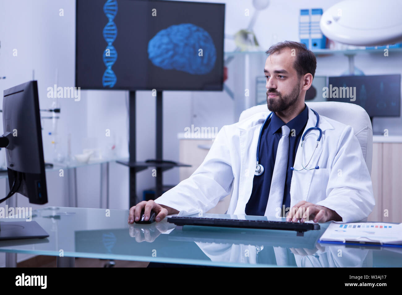 Young medic working on his computer using mouse and keyboard. Medicine ...