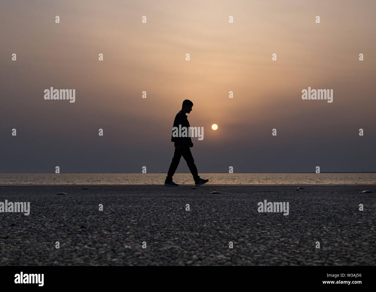 Man walking at sunset Stock Photo - Alamy