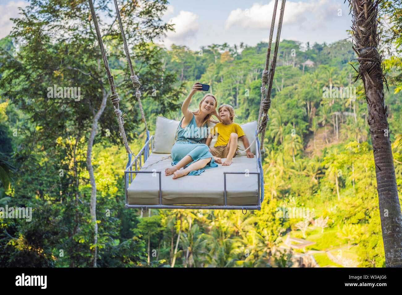 Mother and son swinging in the jungle rainforest of Bali island ...