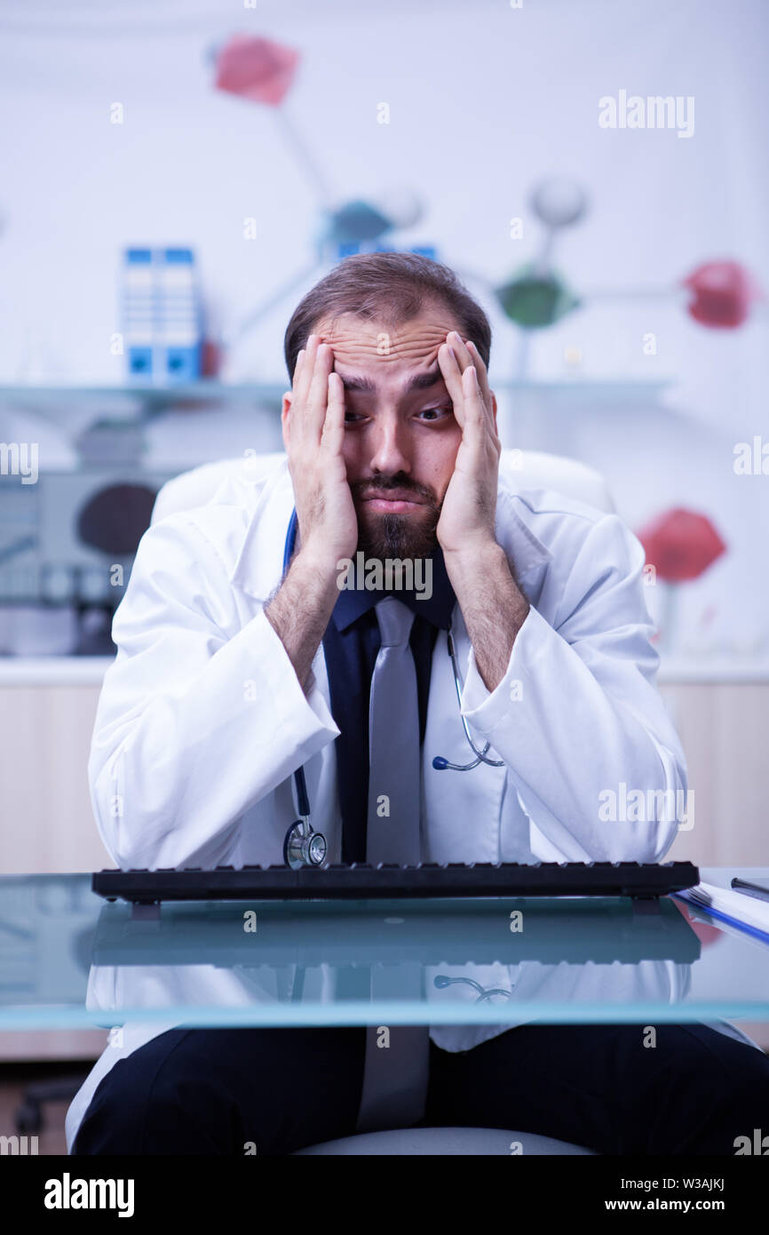 Portrait of young burnout doctor in his hospital cabinet. Young doctor ...