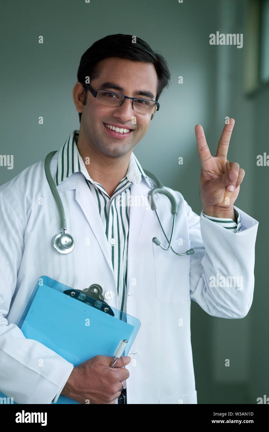 Portrait of a male doctor showing V Sign Stock Photo - Alamy