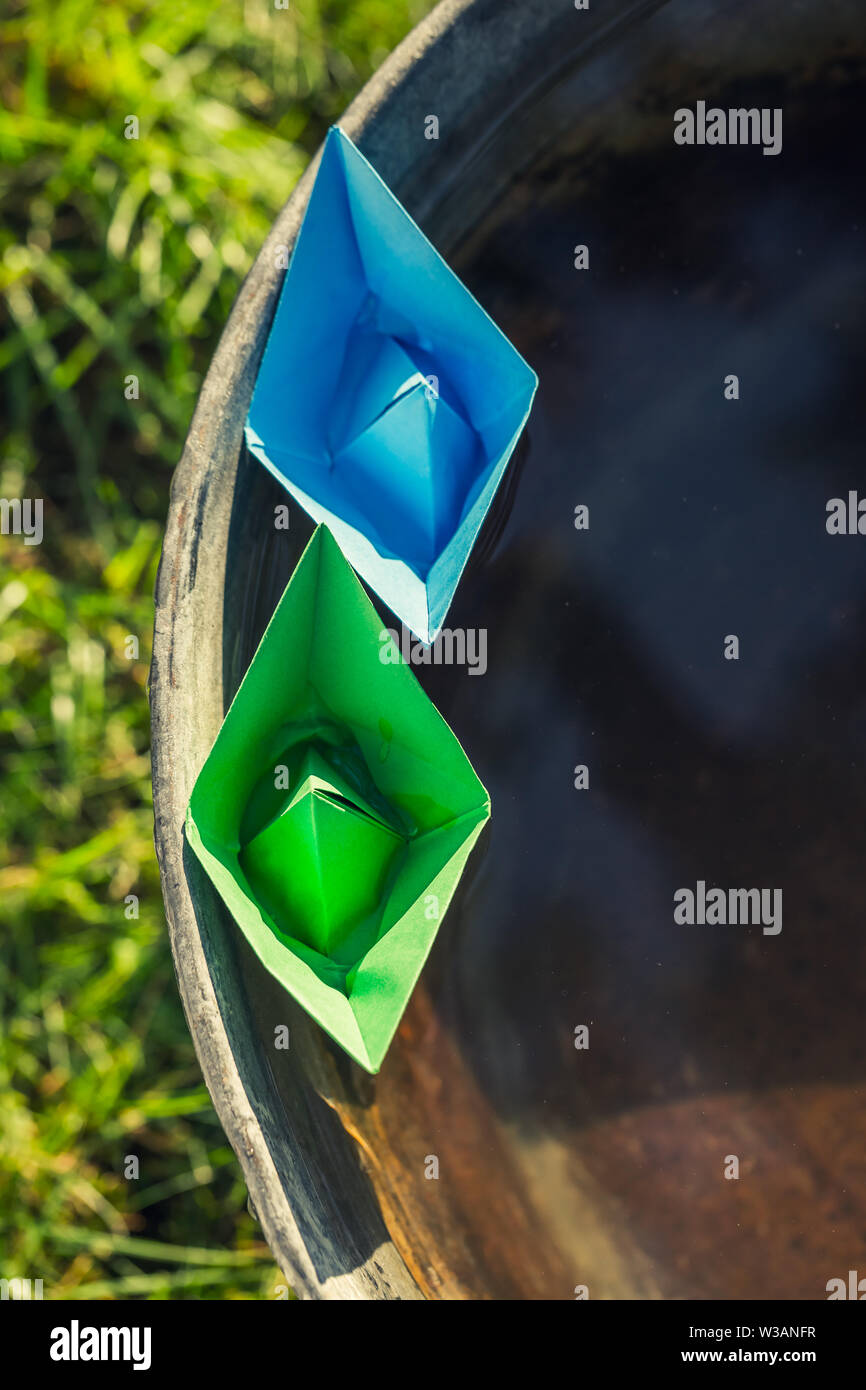 Origami color paper boats quietly floating on water in summr Stock ...