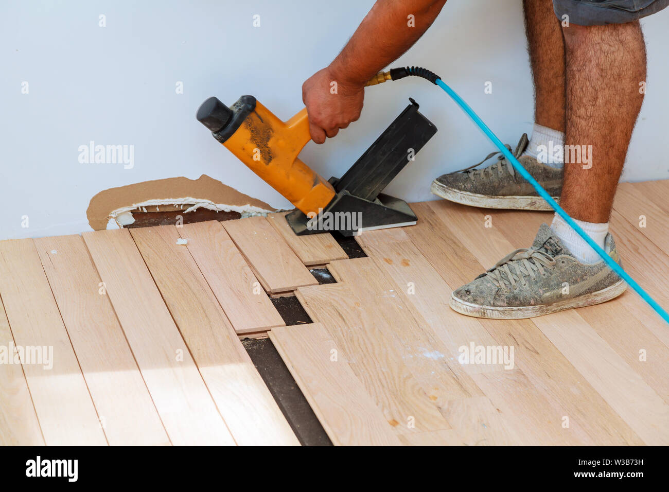 Carpenter worker installing wood parquet board during flooring work ...