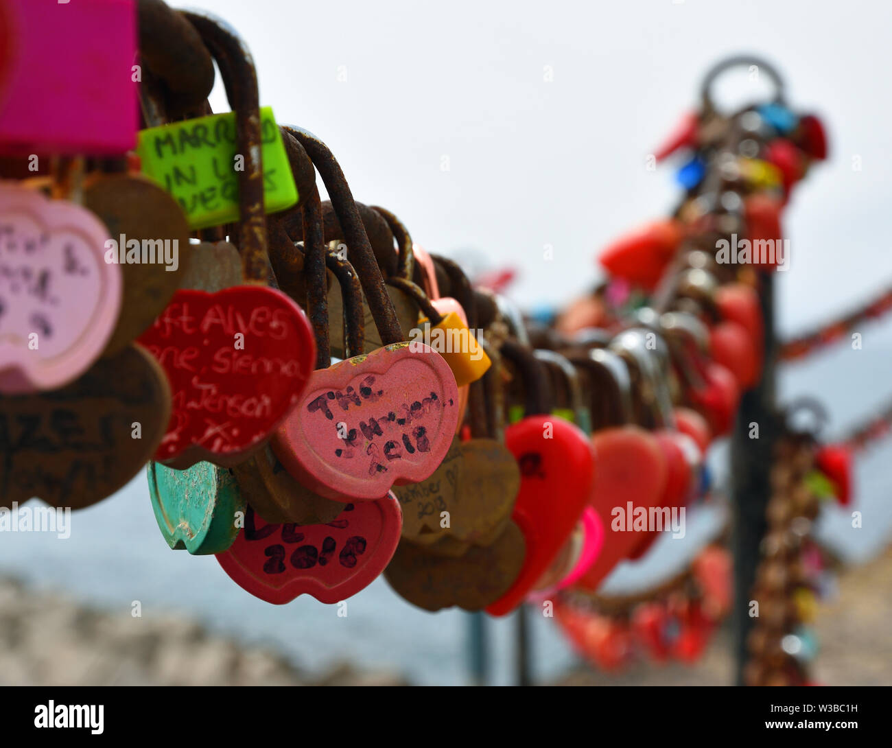 Multi coloured Padlocks on chain fence Stock Photo - Alamy